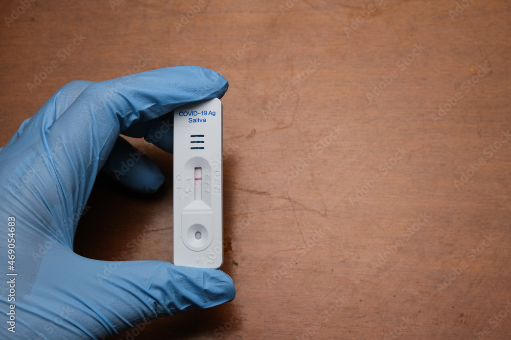 A hand holding Covid-19 saliva self test kit showing negative result ...