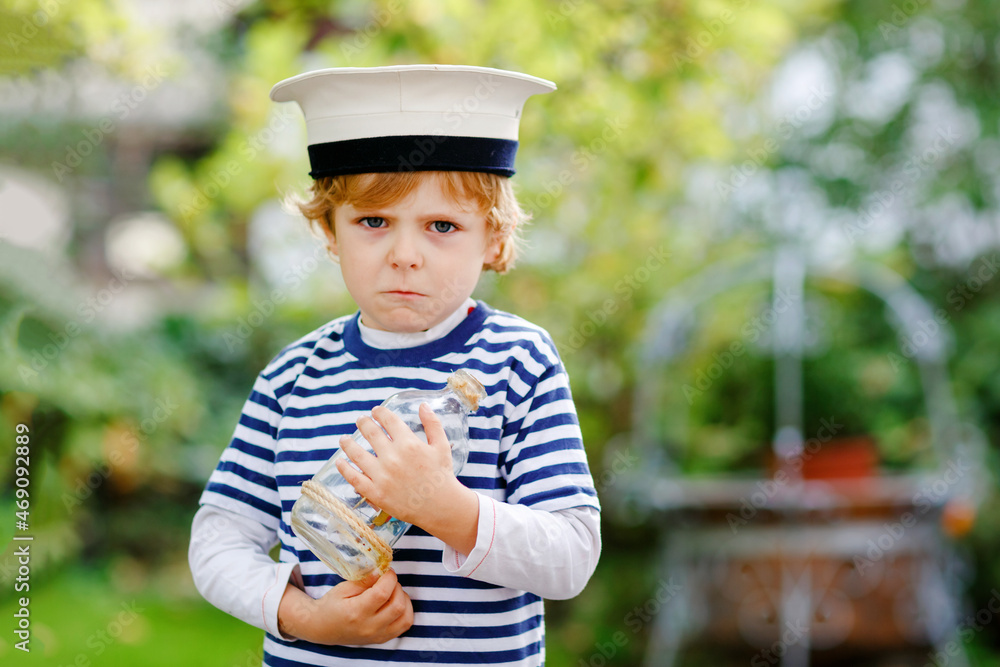 Sad crying little kid boy in sailor capitain hat and uniform playing ...