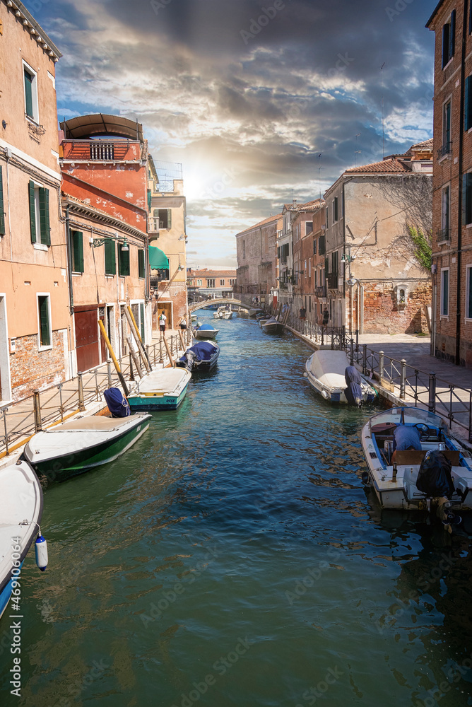 Nautical vessels moored on narrow water canal with bridge between ...