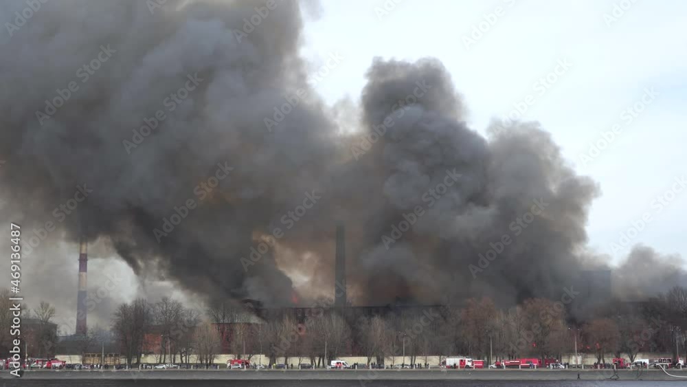 Big house is on fire. Lots of fire trucks. River embankment near. Brick ...