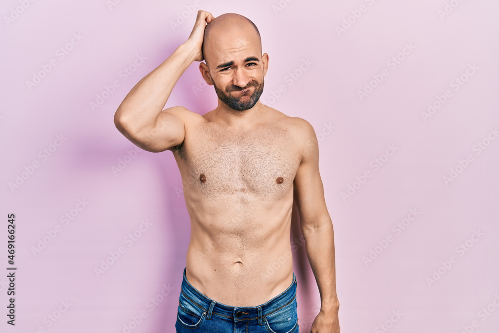 Young bald man standing shirtless confuse and wonder about question ...