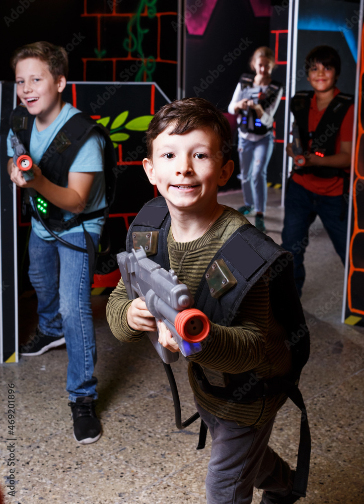 smiling active young boy aiming laser gun at other players during ...