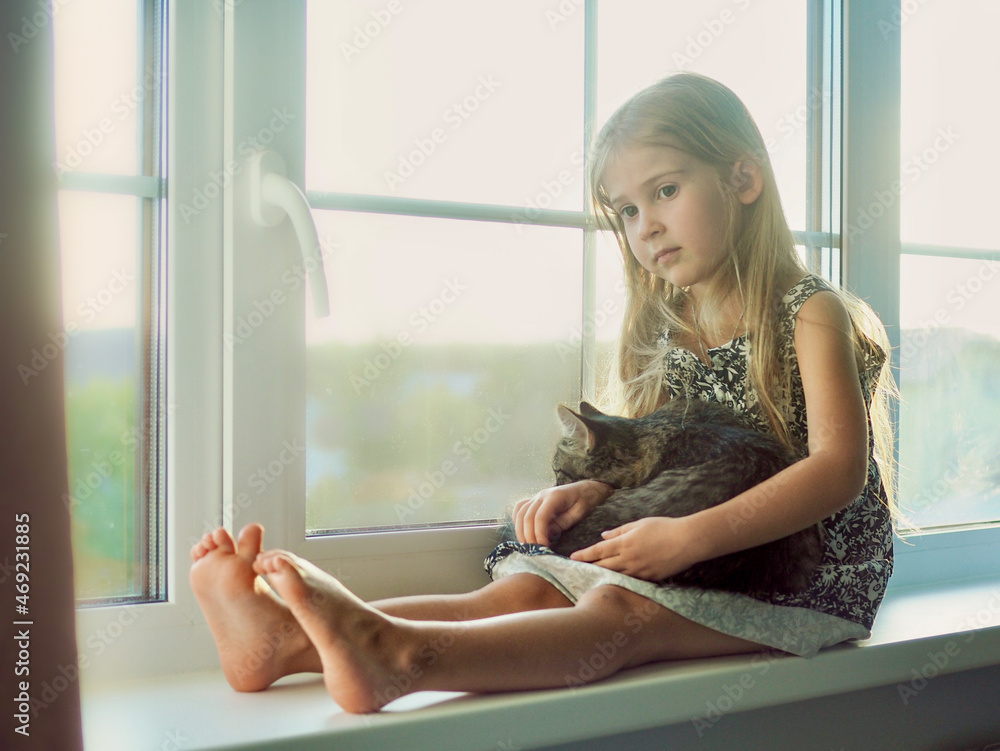 Cute little girl sitting on windowsill with fluffy cat. Best friends ...