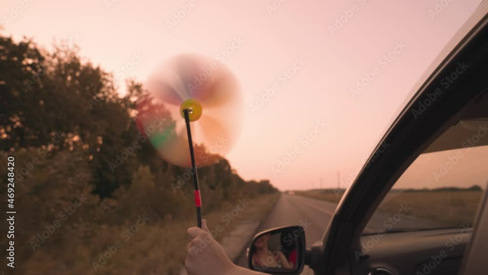 free girl waving a pinwheel out of the car window in wind, travel ...