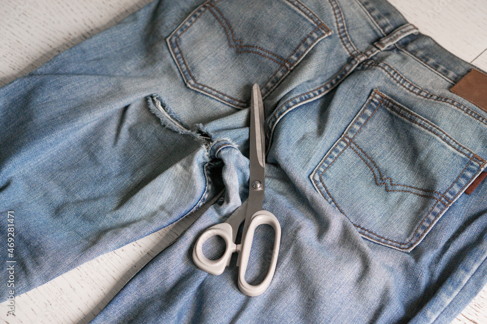 Old torn jeans are spread out on the table, ready to be repaired. Woman ...