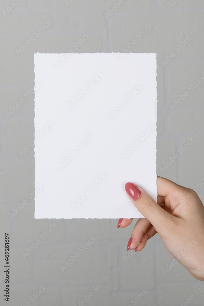 Woman hands holding blank paper sheet A5 size or letter on grey wall ...