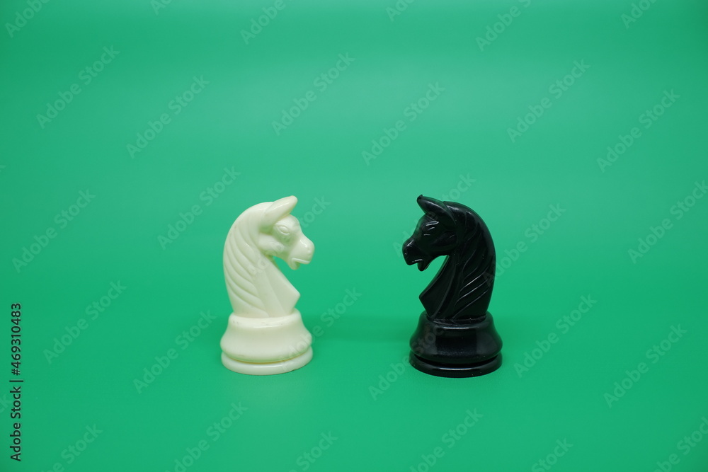Two horse or knight chess pieces, black and white facing each other. In ...
