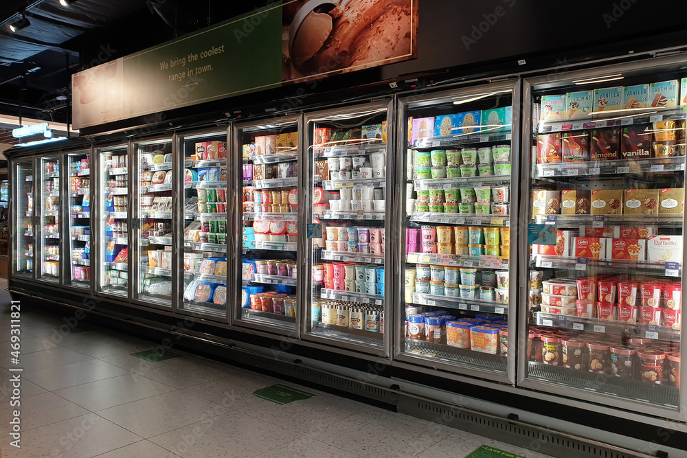 Interior view of huge glass fridge with various brand ice cream in ...