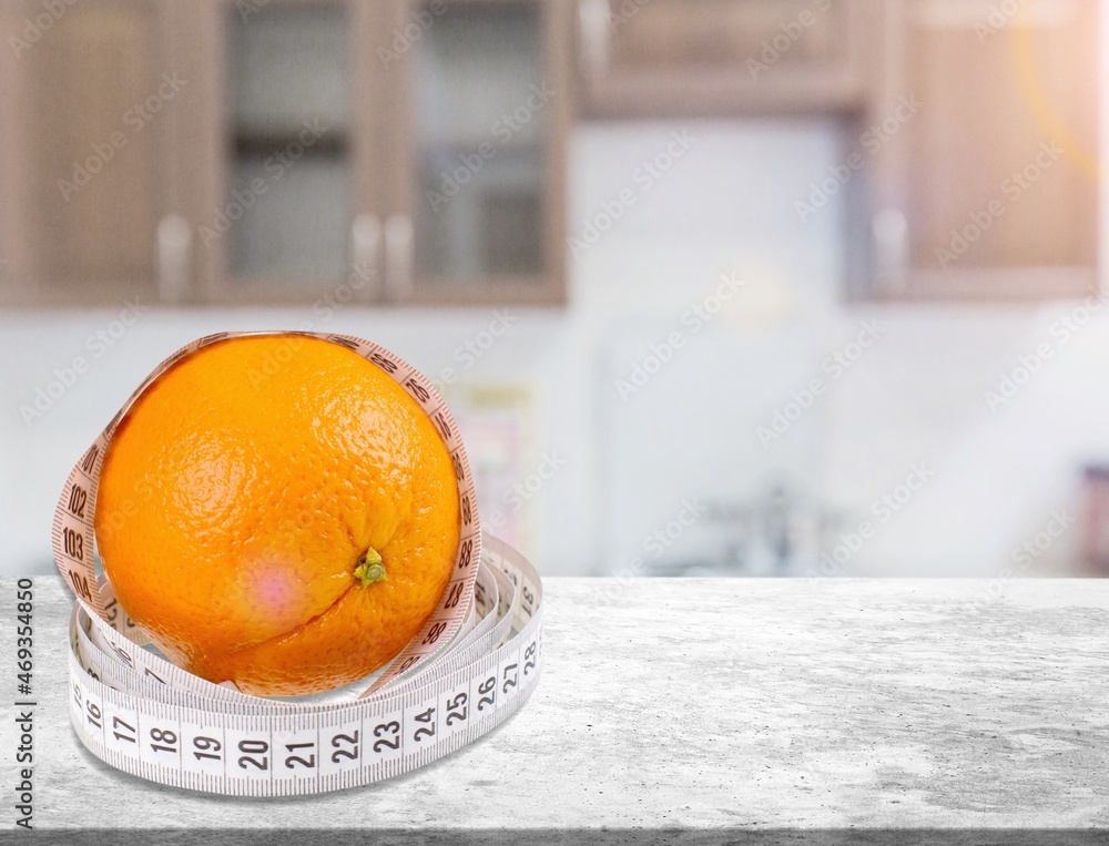 Fruit orange is wrapped with measuring tap as a symbol of cellulite on ...
