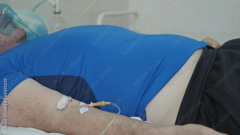 Sick man in a hospital bed. An intravenous drip is installed in the arm ...