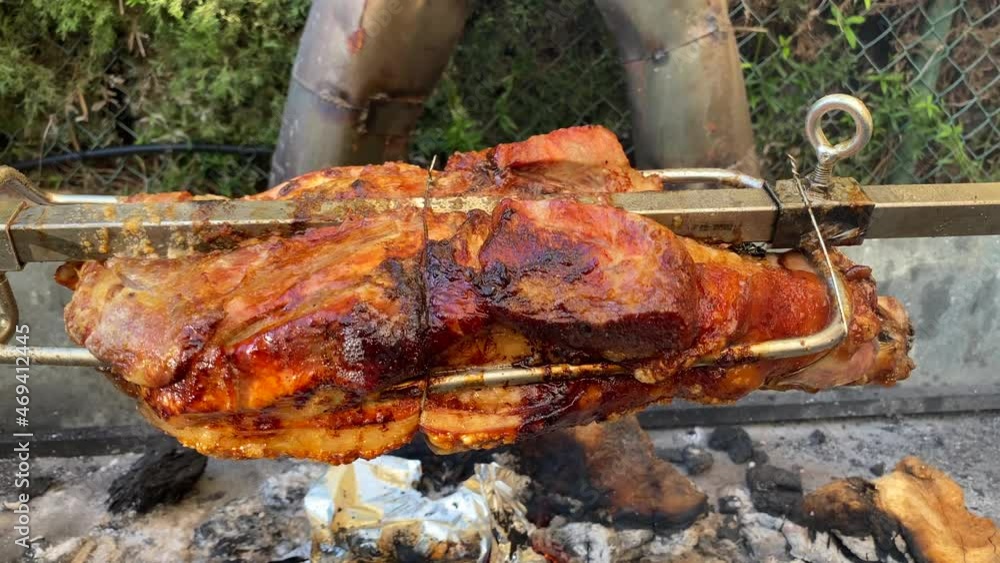 Vidéo Stock Roasting suckling pig on a spit metal rotating stick over ...