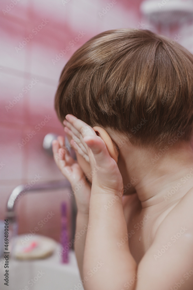 Foto de Little boy washes in a bathroom. Little boy washing his face in the bathroom. Going to ...