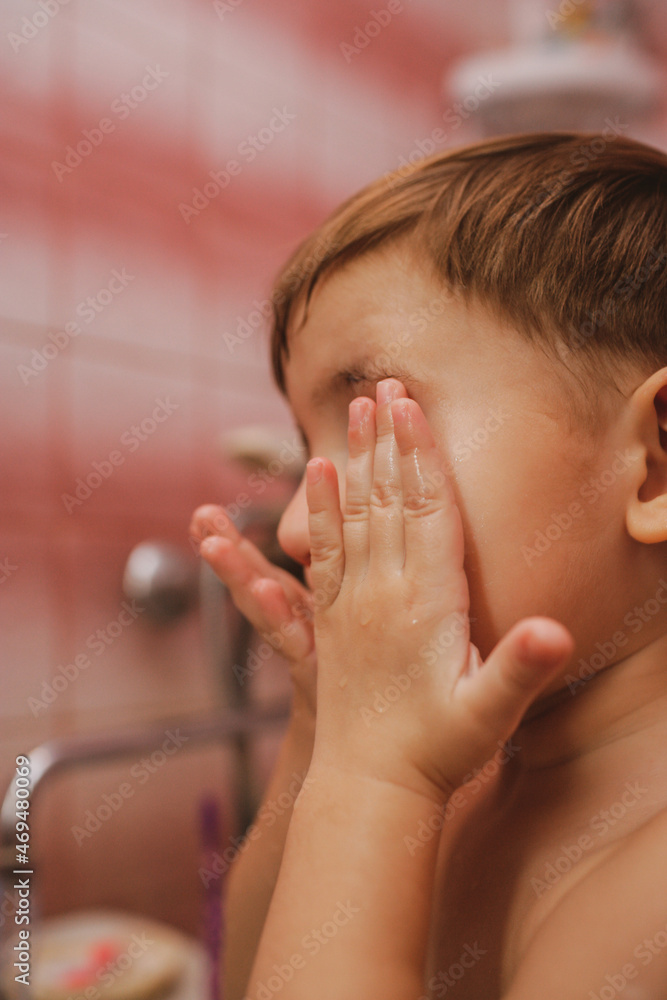 Foto de Little boy washes in a bathroom. Little boy washing his face in the bathroom. Going to ...