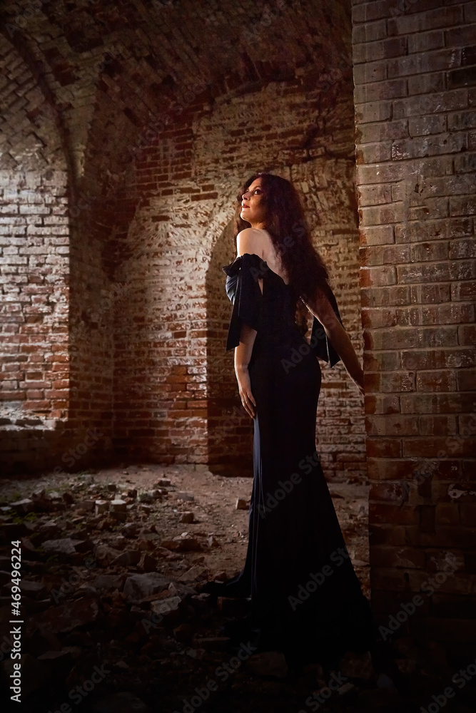 A brunette girl with long hair in an evening dress in a vintage Gothic ...