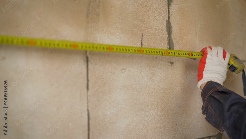 The master measures the distance on the wall with a tape measure ...