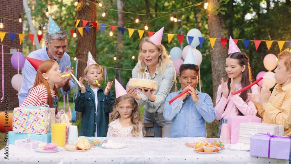 Happy children in party hats with party blowers at the birthday party ...