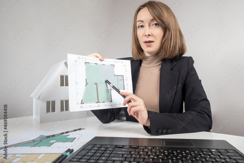 Woman architect demonstrates construction drawings. She is holding a ...