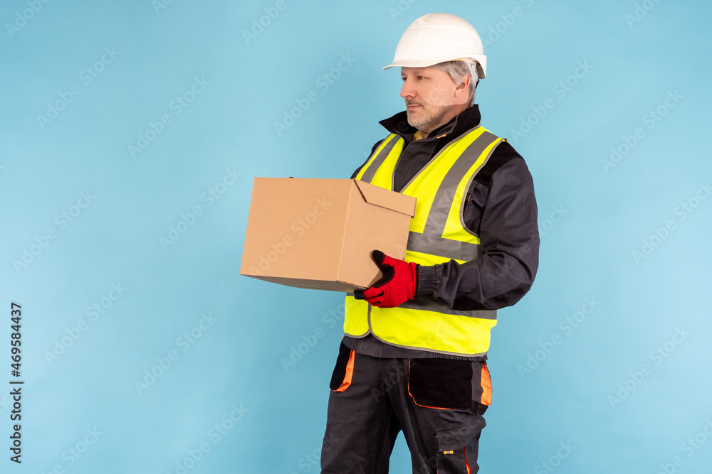 Builder is holding a closed carton box. Worker with a box in his hands ...