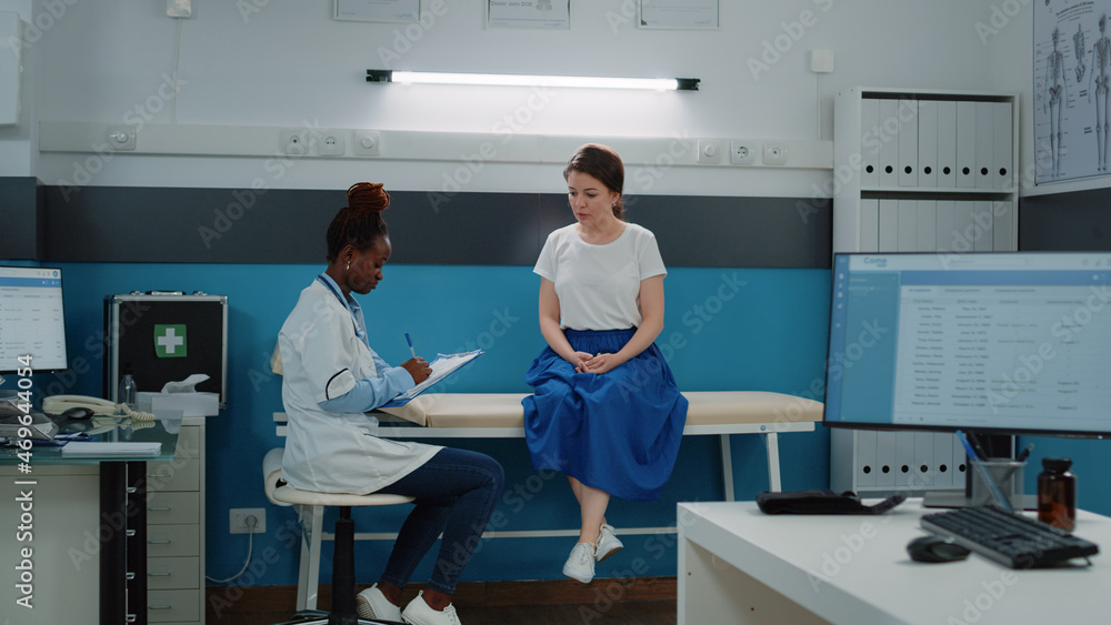 Young patient on bed talking to doctor for annual checkup visit and ...