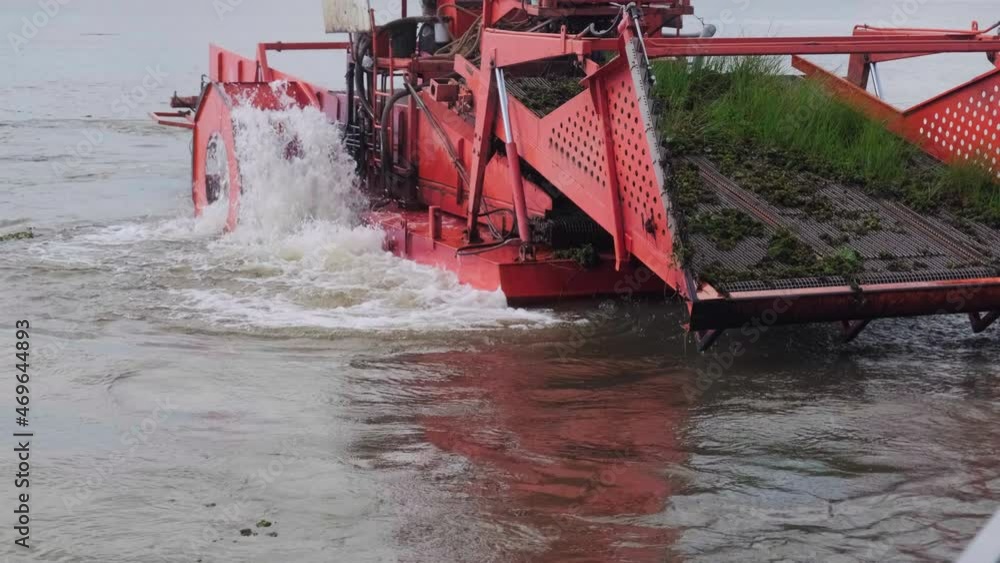 Worker on a weed clearing water tractor (or aquatic weed harvester ...