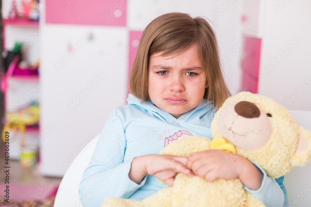 Cute little caucasian crying girl with teddy bear in bedroom. Sad ...