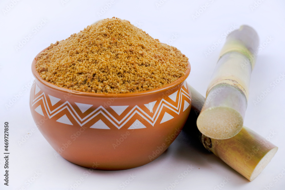 Jaggery powder and sugarcane isolated on white background. Jaggery is ...