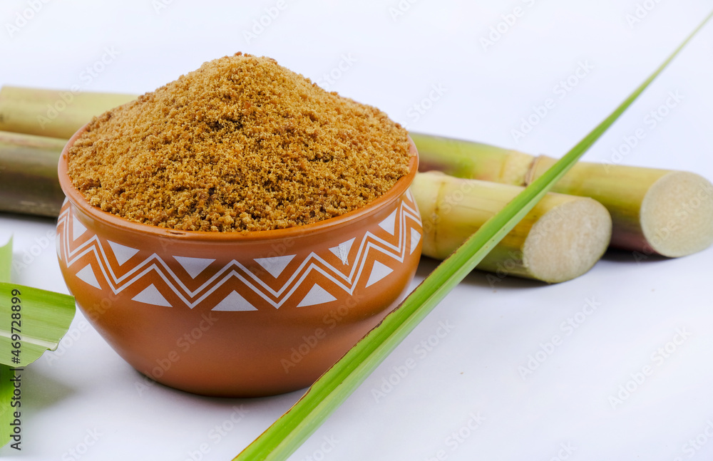 Jaggery powder and sugarcane isolated on white background. Jaggery is ...
