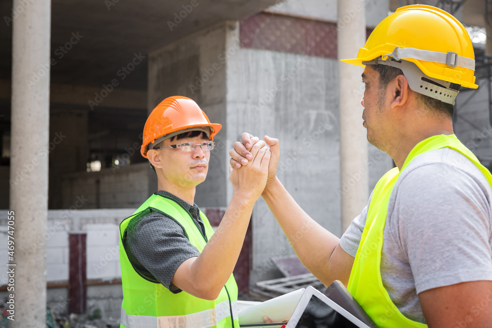 Builders greeting each other with handshake on construction site ...