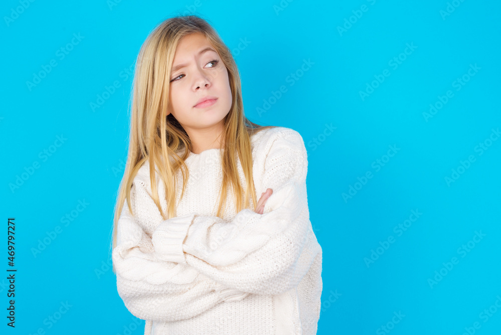 Displeased caucasian little kid girl wearing wool jersey over blue ...