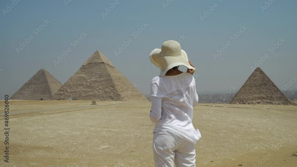 Tourist woman with white straw hat in front of The Great Giza pyramids ...