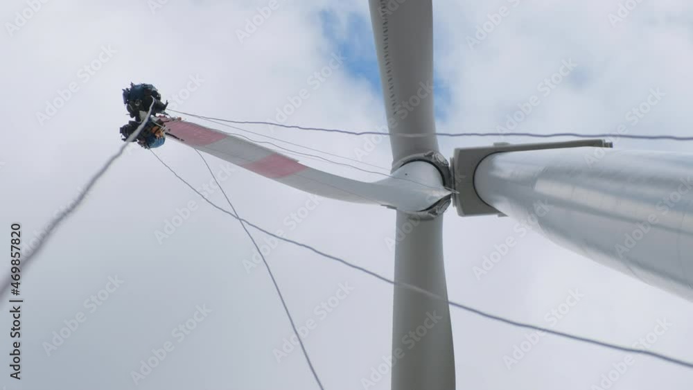 Service workers fix wind-driven generator blade sitting on climber ...