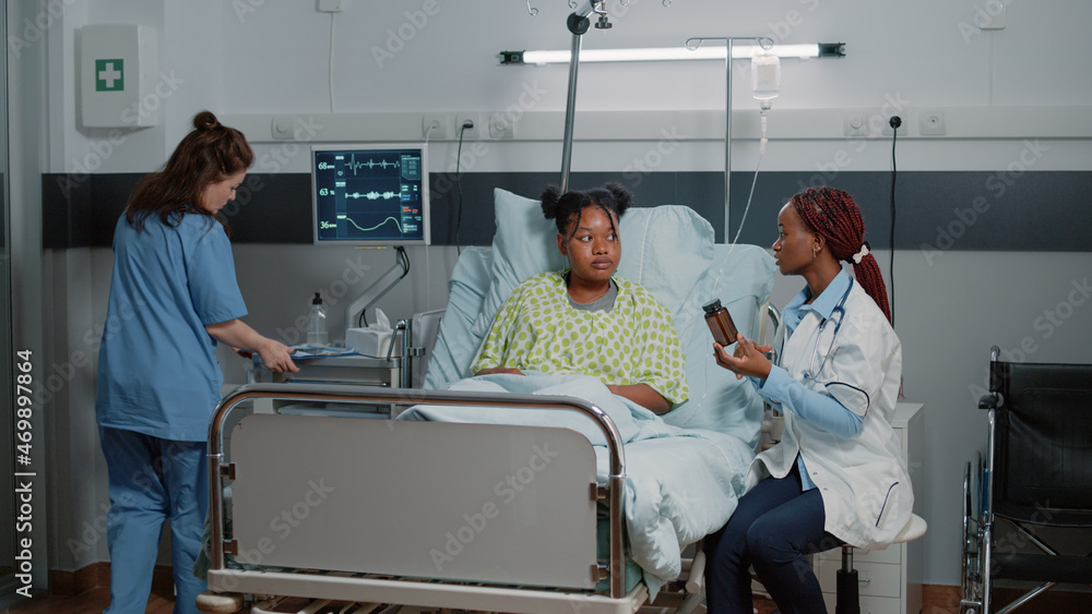 Woman working as doctor giving bottle of pills to patient in hospital ...