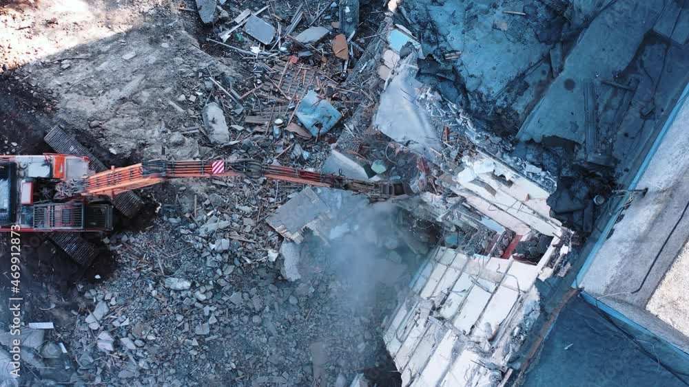 Long claw of an excavator destroys the concrete parts of the building ...