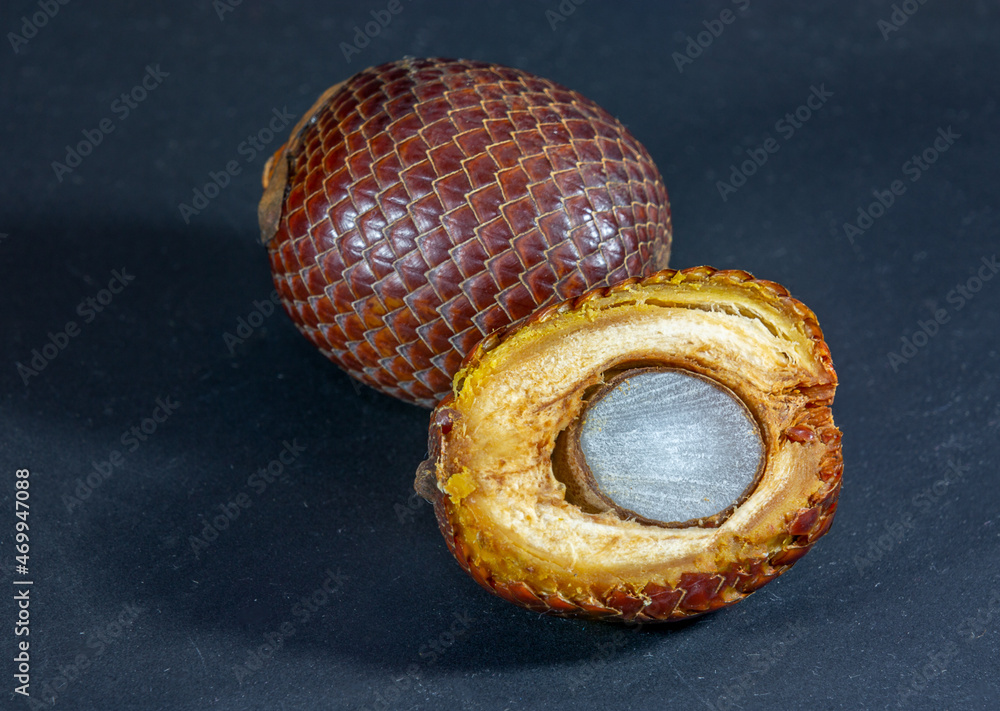 Ripe Buriti fruit (Mauritia flexuosa) isolated in macro and cut in half ...