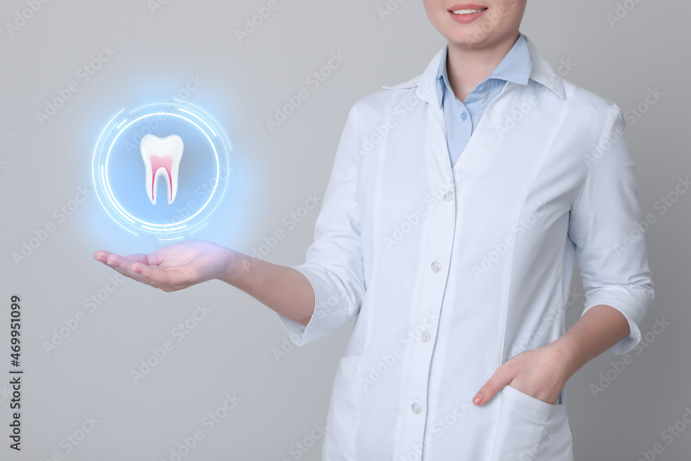 Dentist showing virtual model of tooth on light grey background ...