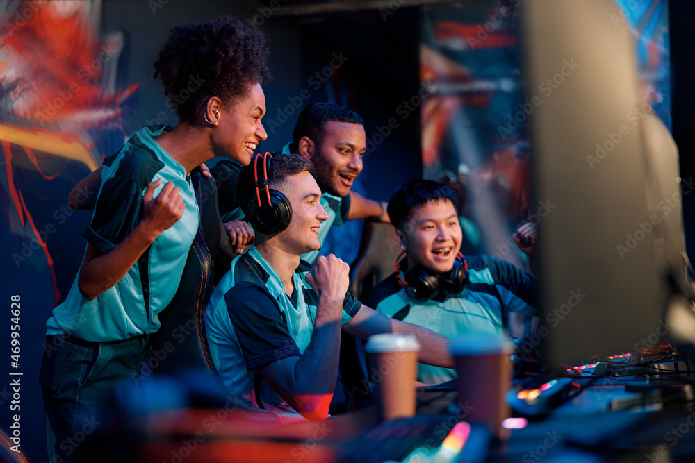 Side view of excited professional cyber gamers team celebrating success ...