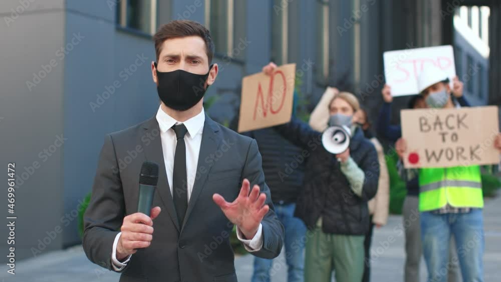Male journalist correspondent wearing suit reporting live near building ...