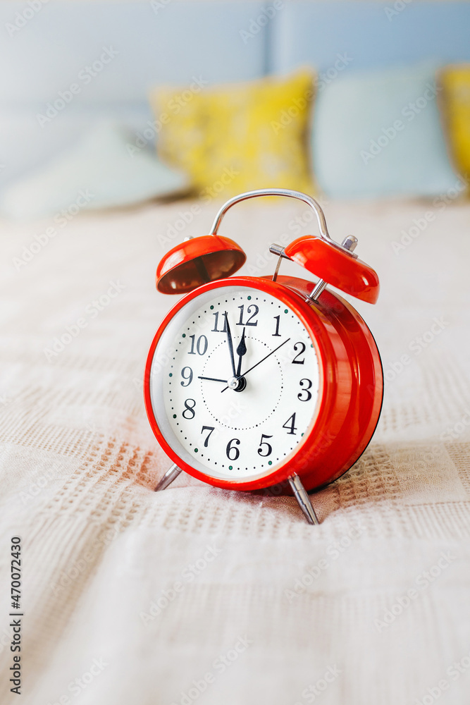Red vintage alarm clock in the bedroom on the bed is a necessary ...