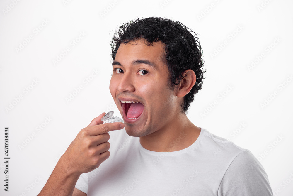 young man with dark skin, mexican, holds in his hand his dental palate ...