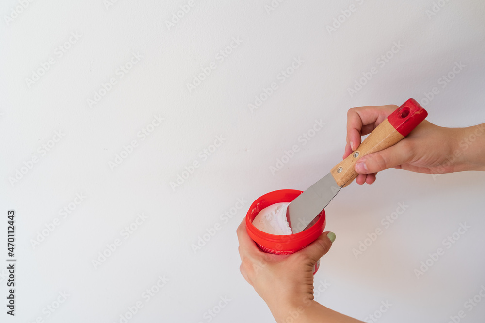 Woman holding putty wall with a spatula on white background. Human ...