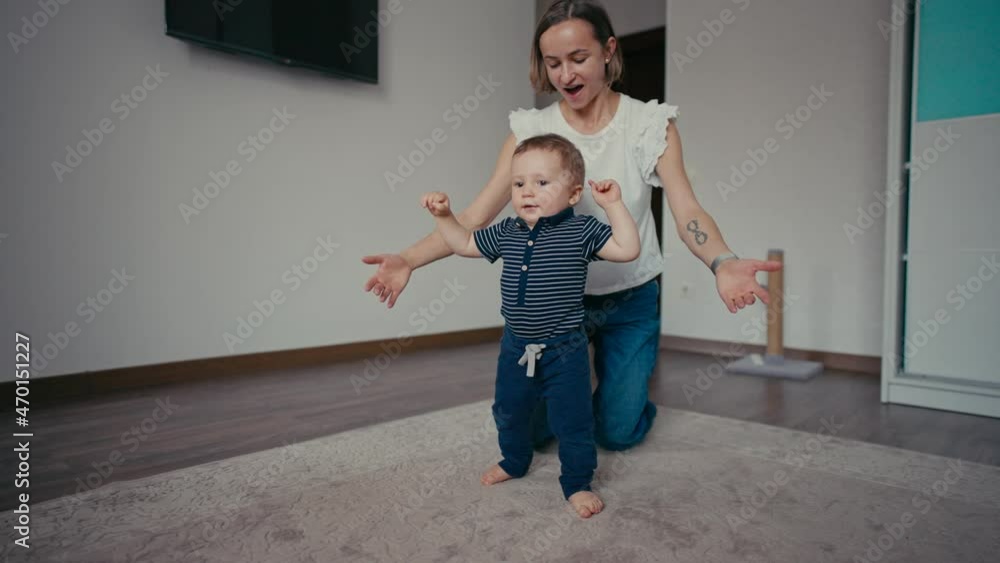 Cute smiling baby boy learning to walk. Baby's First Steps. Baby making ...