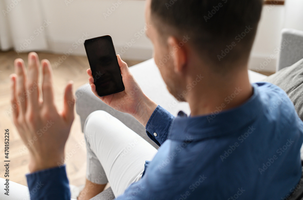 Young man using smartphone for video call, phone with black empty ...
