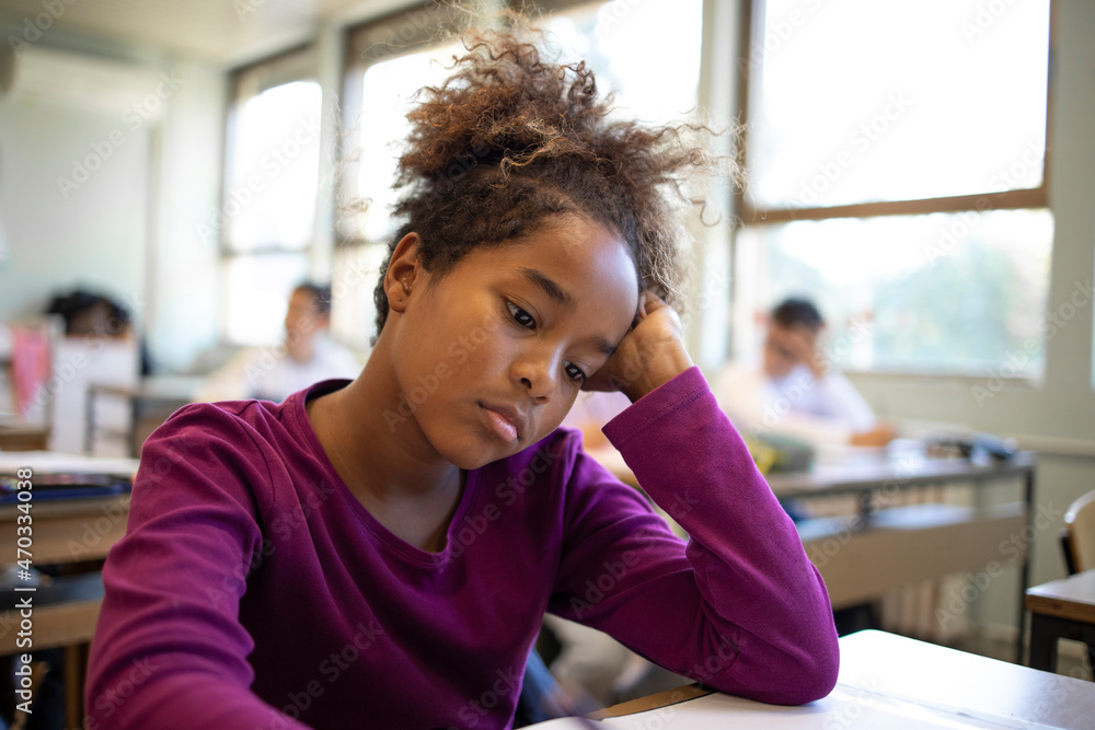 Portrait of schoolgirl feeling sad and neglected by her schoolmates in ...