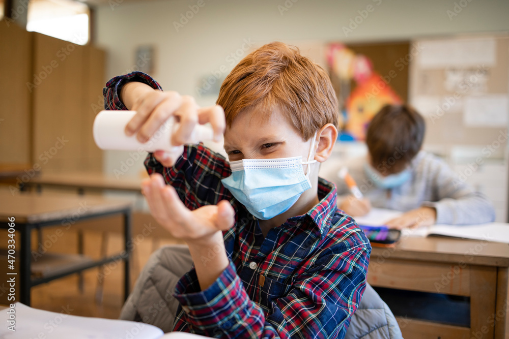 School children wearing face masks and disinfecting their hands in ...
