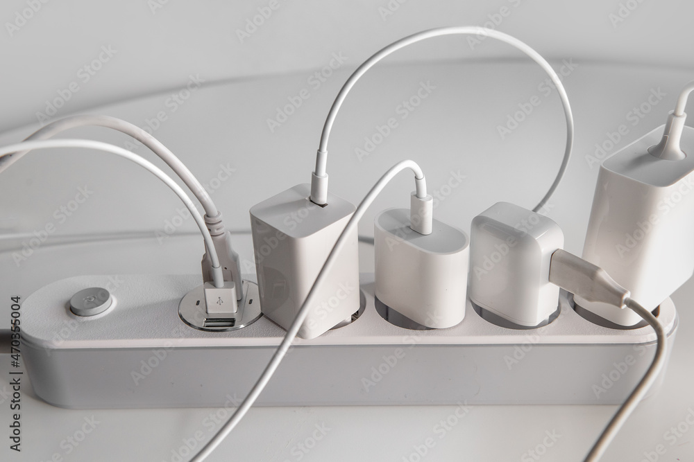 Many chargers plugged into maltiple electrical outlet on white ...