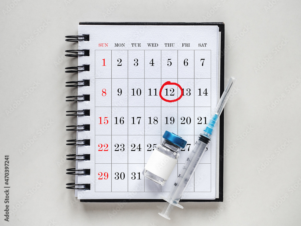 Syringes, injection vials and a calendar page lying on the table. Close ...