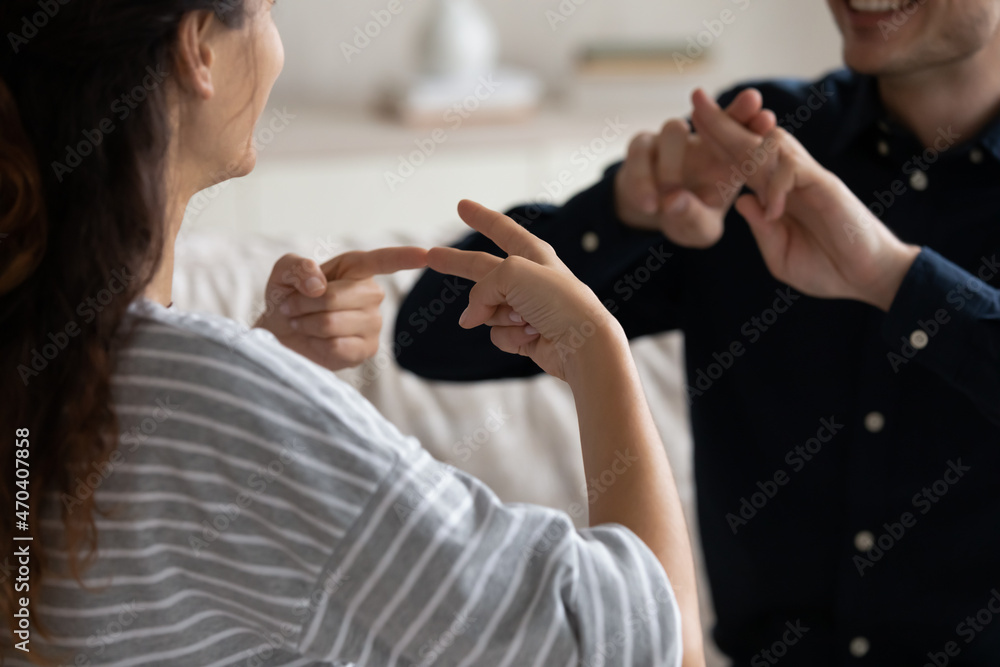 Young positive couple sit on sofa at home communicating using sign ...