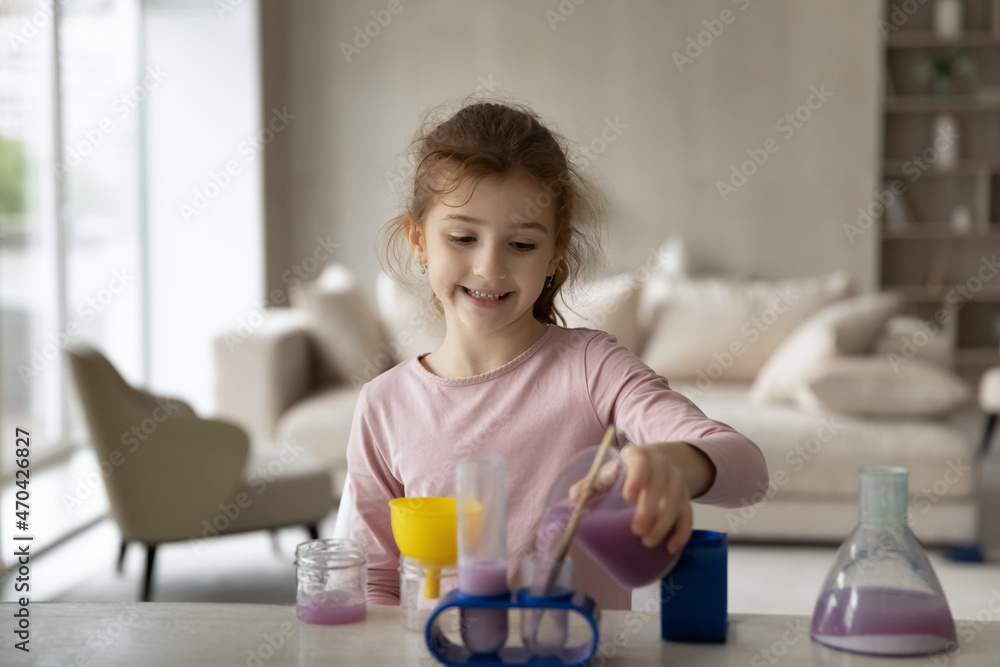 Curious smiling little girl playing with toy laboratory, making funny ...