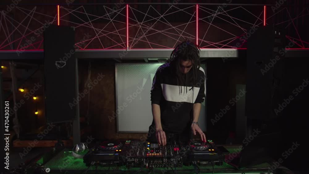 Stylish energetic arab male dj with dreadlocks in headphones mixing ...