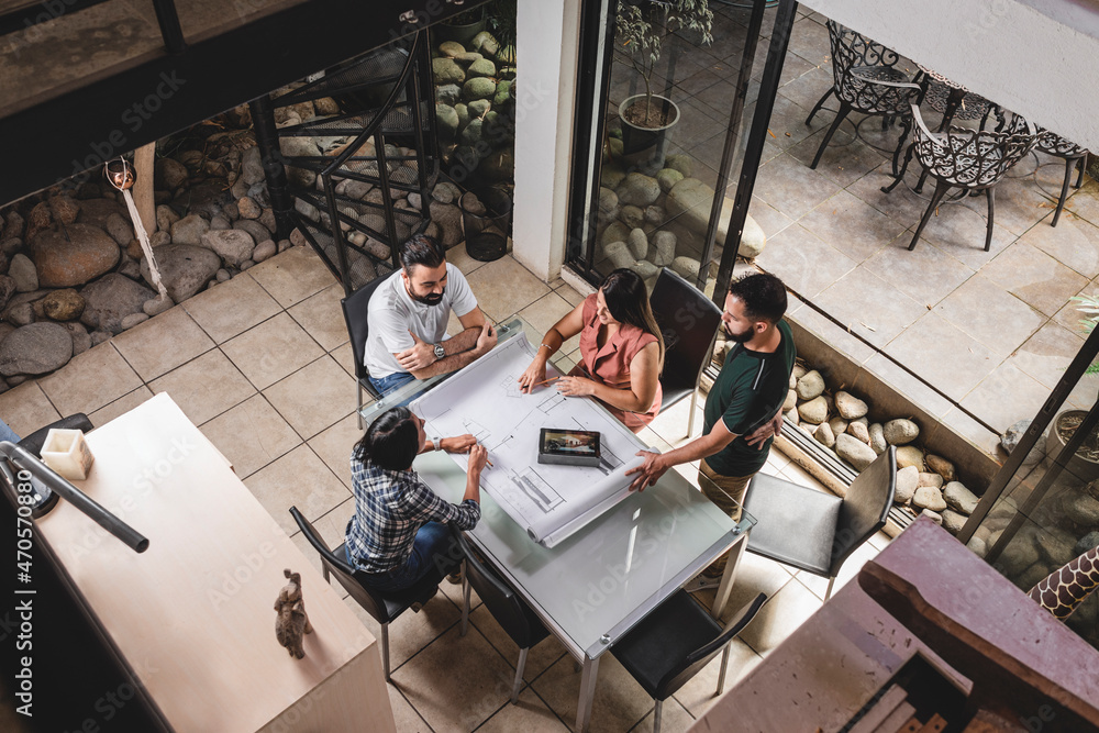 Vista superior de un Grupo de profesionales analizando planos constructivos e imágenes de un ...